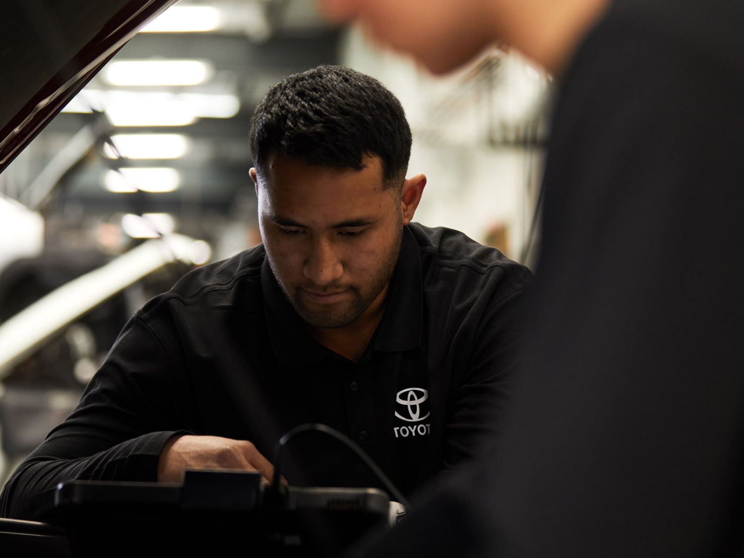 View through a driver’s car window at a focused Toyota technician ...